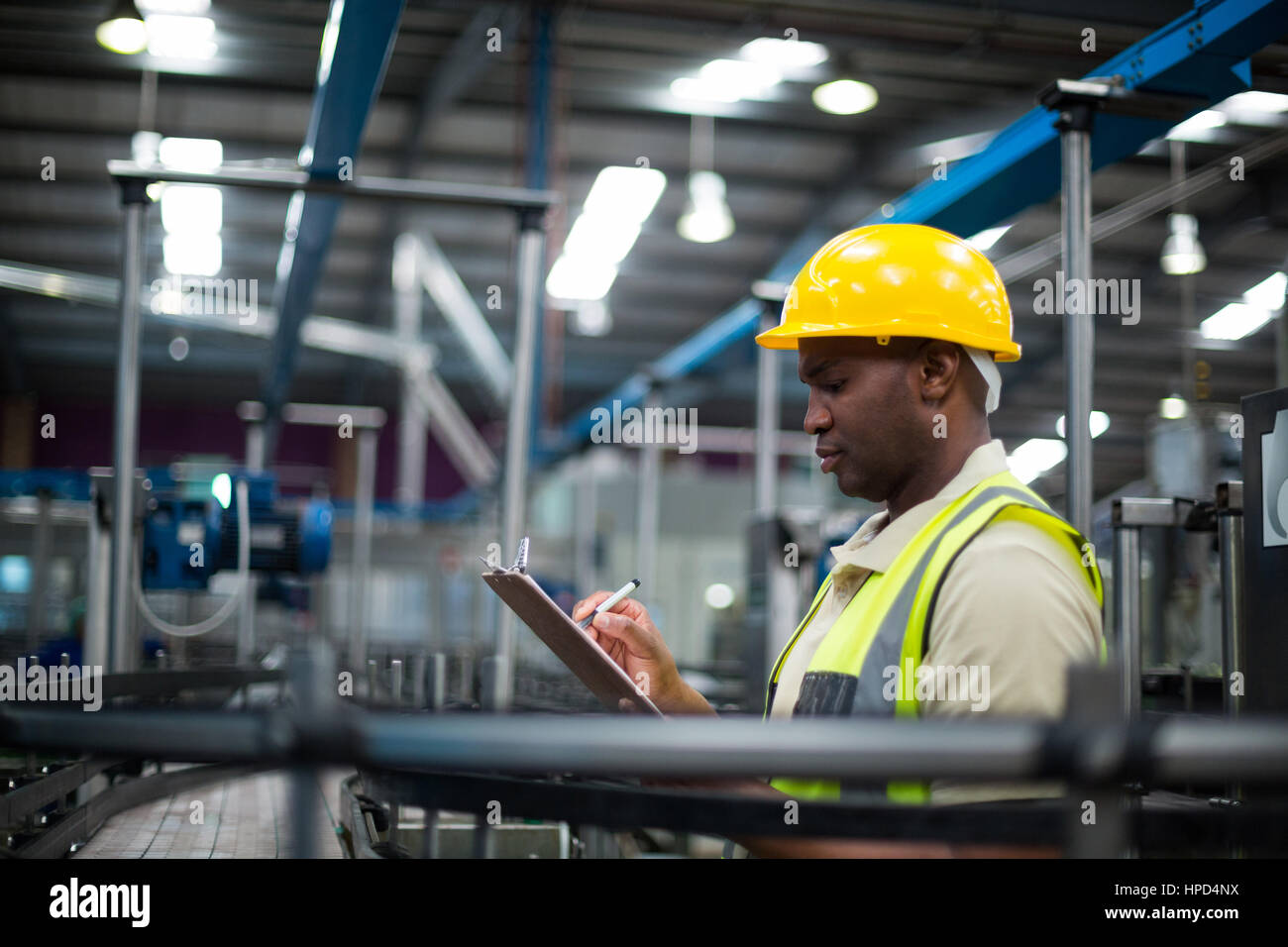 Factory worker writing on the clipboard in factory Stock Photo - Alamy