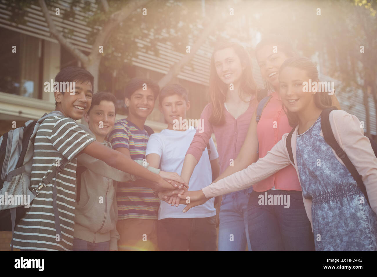 Portrait of happy school kids forming hand stack in campus at school ...
