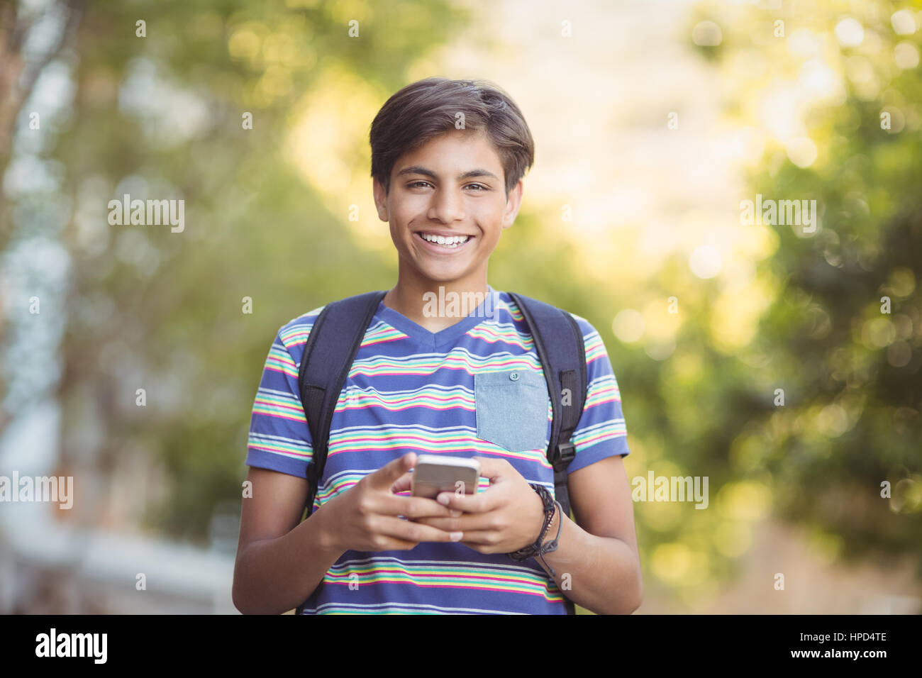Portrait of schoolboy using mobile phone in campus at school Stock ...