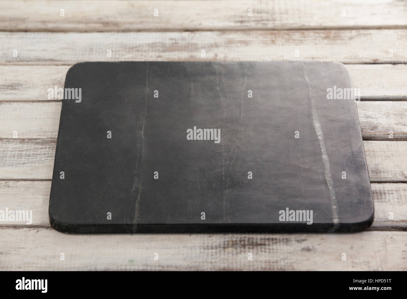 Black slate plate against wooden background Stock Photo - Alamy