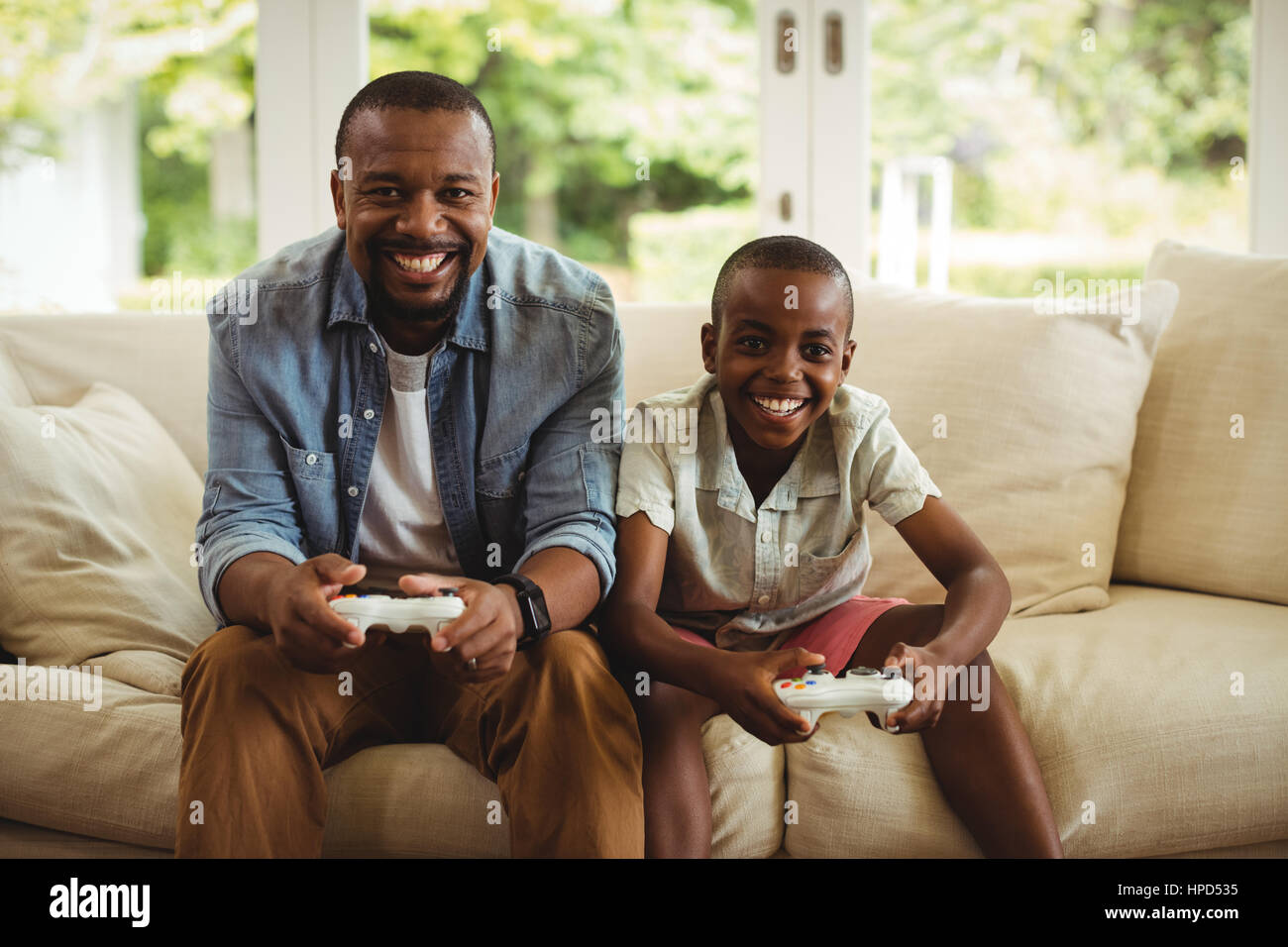 Portrait of father and son playing video game in living room at home ...