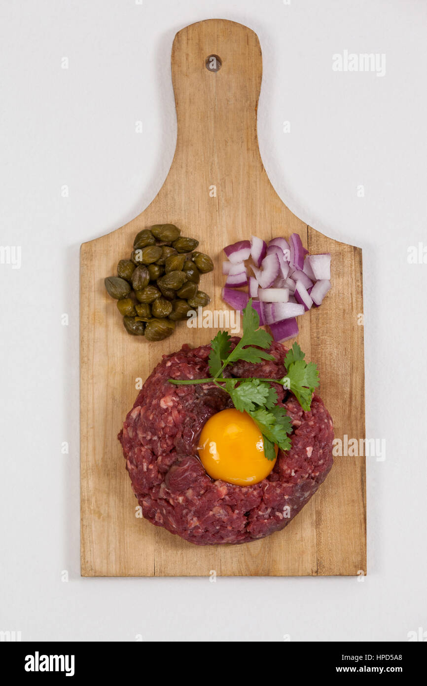 Beef patty, onions and olives on wooden board against white background ...