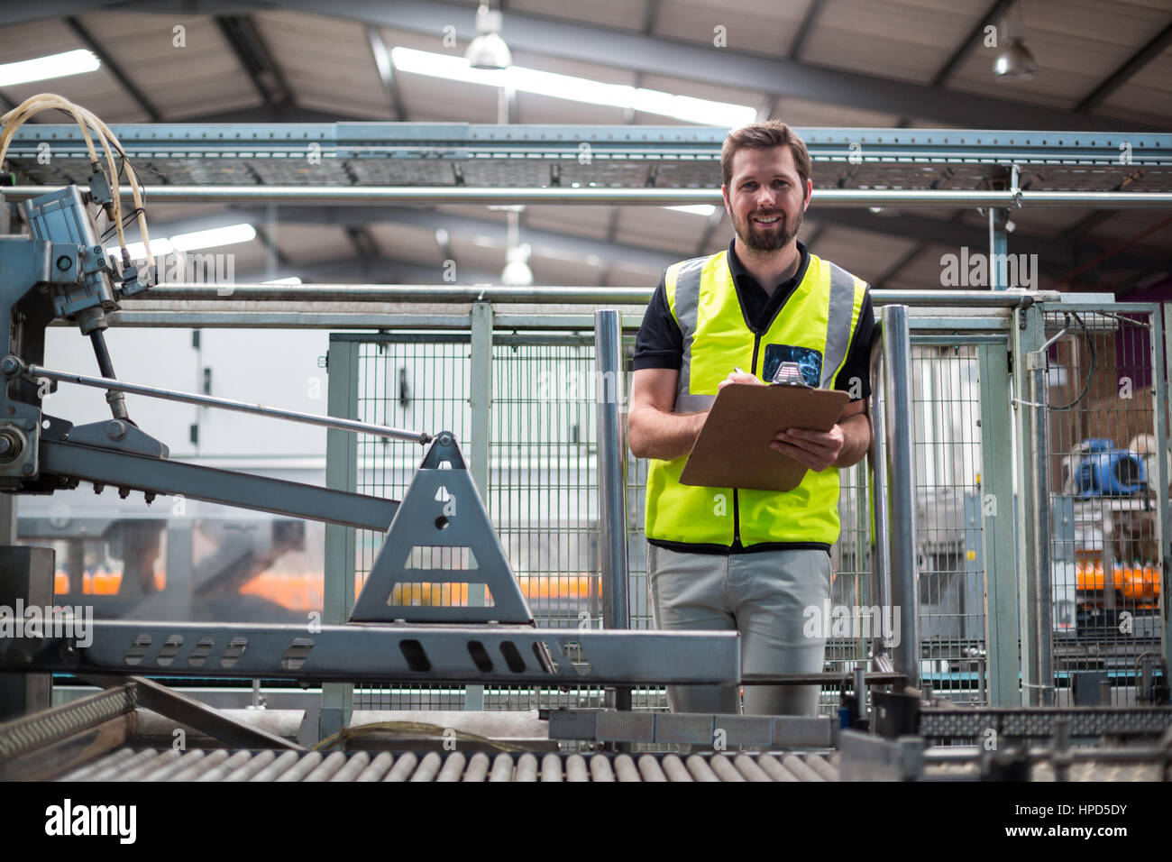 Smiling factory worker writing on clipboard in factory Stock Photo - Alamy