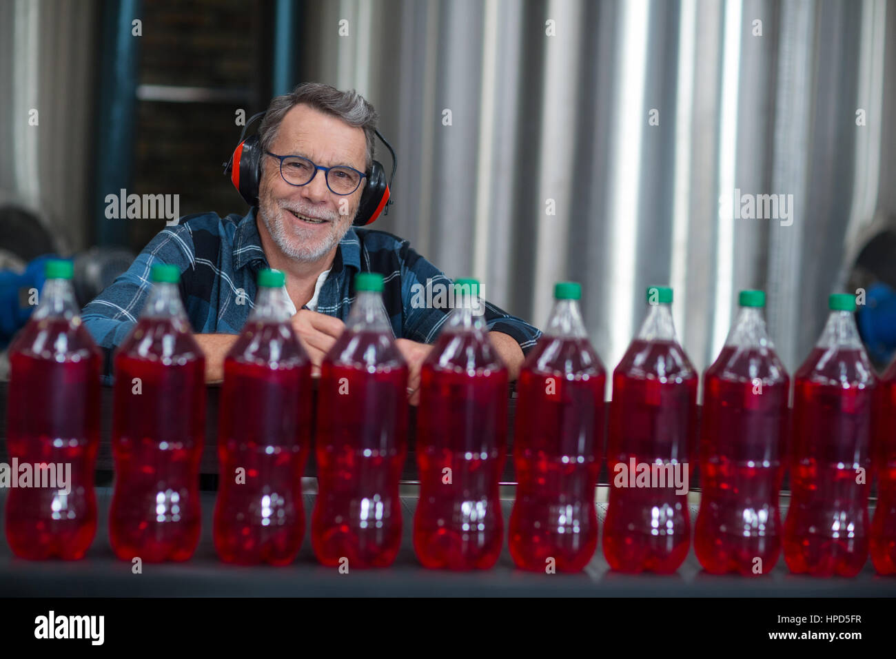 Portrait of male factory worker monitoring cold drink bottles at drinks ...