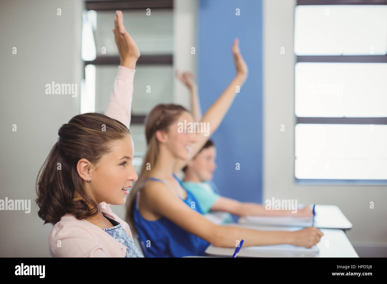 Student raising hand in classroom at school Stock Photo - Alamy