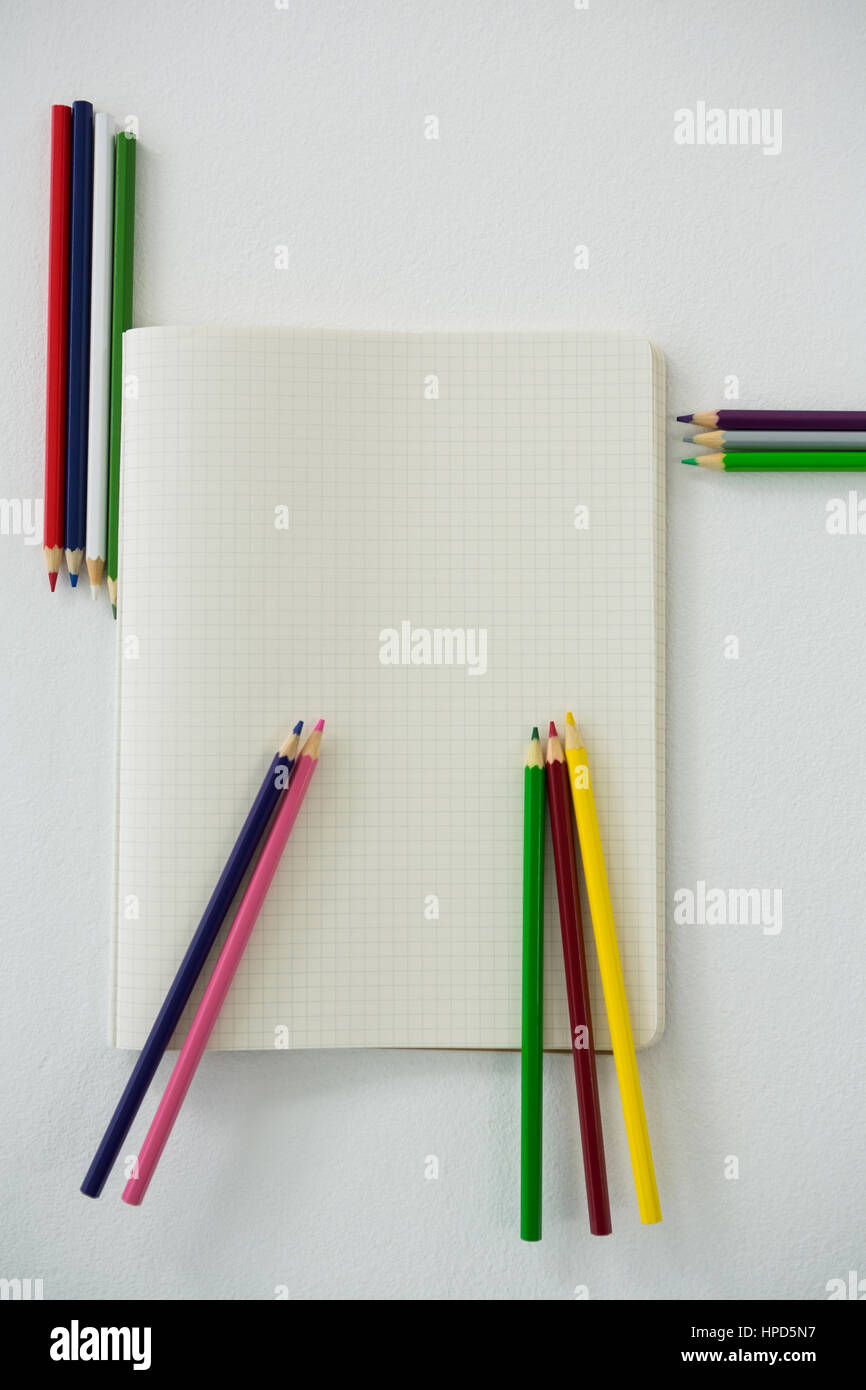 Colored pencils with book on white background Stock Photo - Alamy