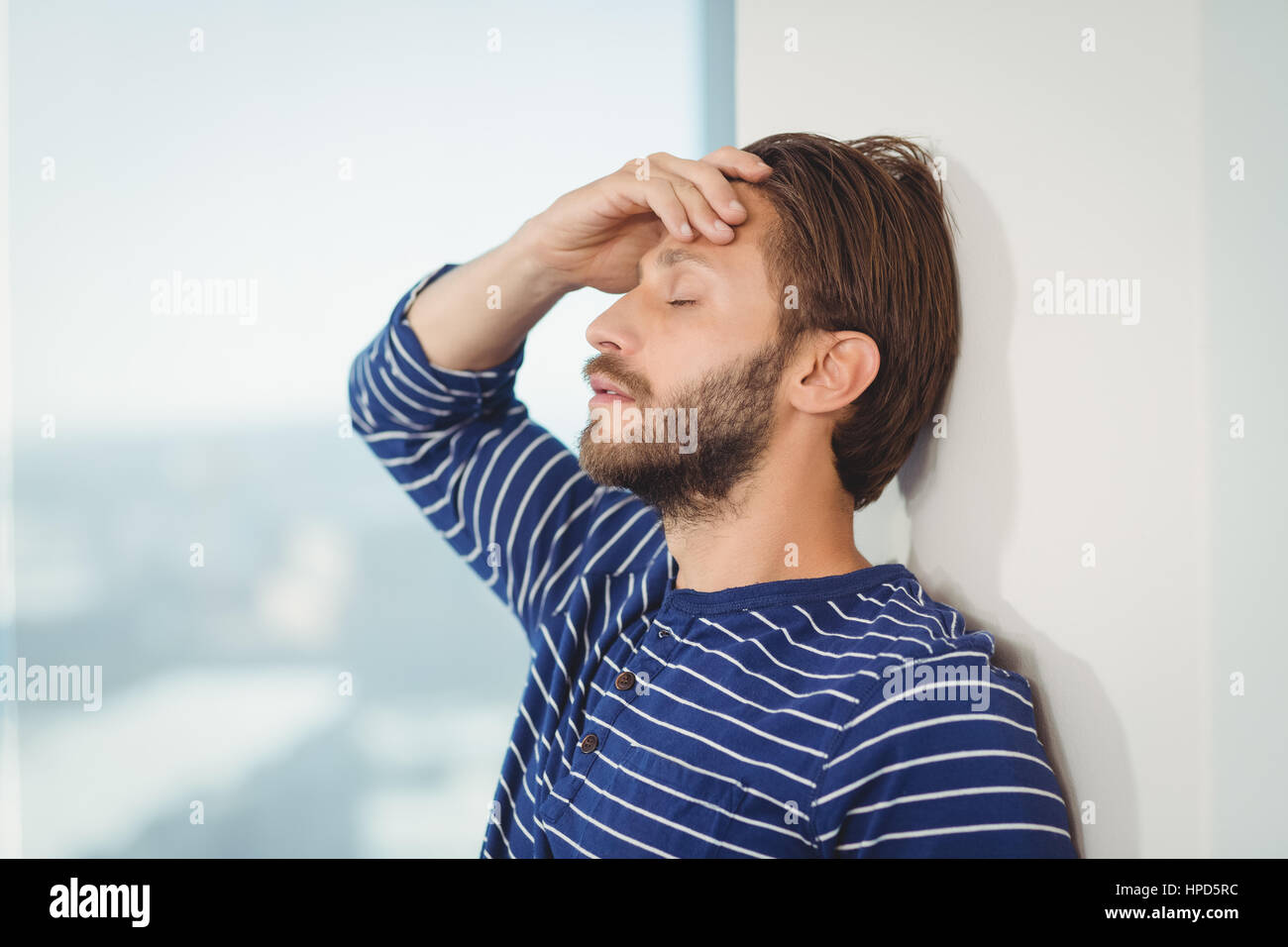 Sad executive leaning on wall in office Stock Photo - Alamy