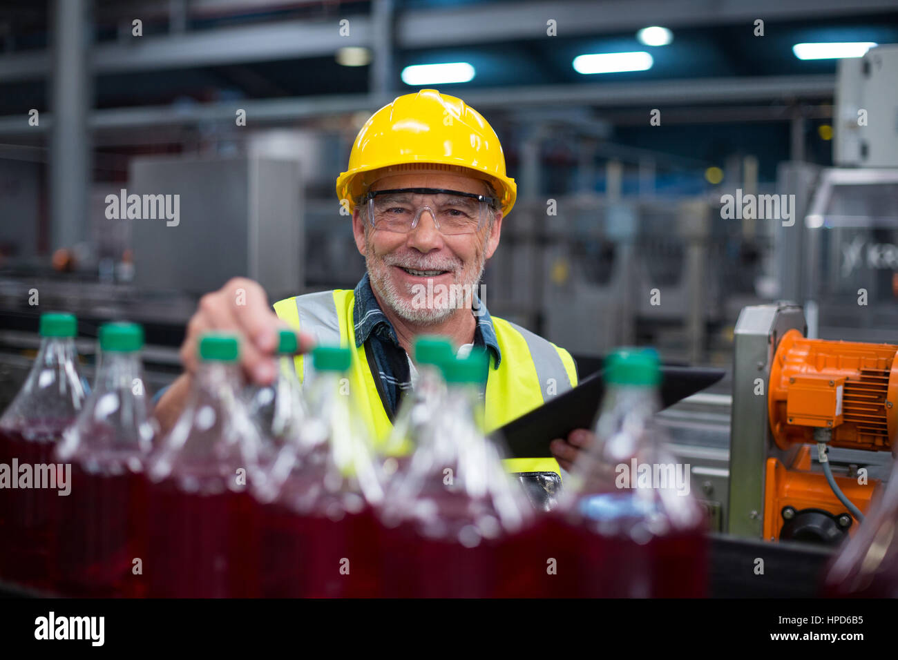 Portrait of male factory worker monitoring cold drink bottles at drinks ...