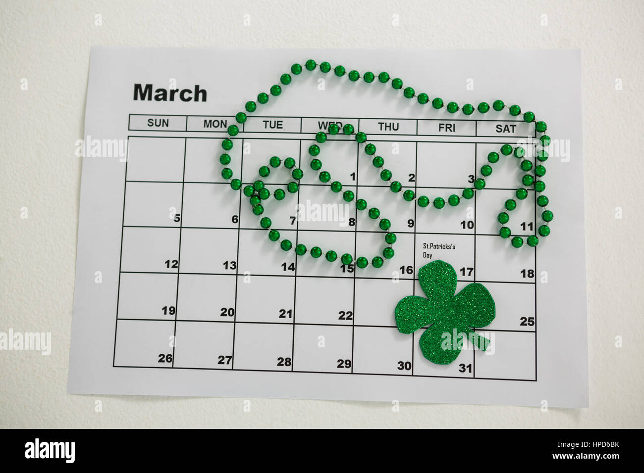 St. Patricks Day shamrock and beads kept on calendar on white ...