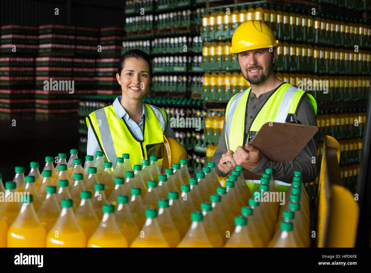 Portrait of two factory workers monitoring cold drink bottles at drinks ...