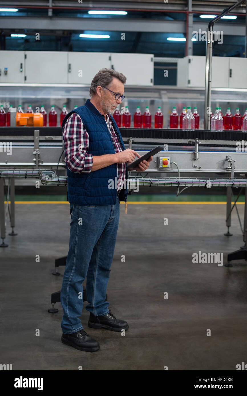 Factory worker using digital tablet next to production line in drinks ...