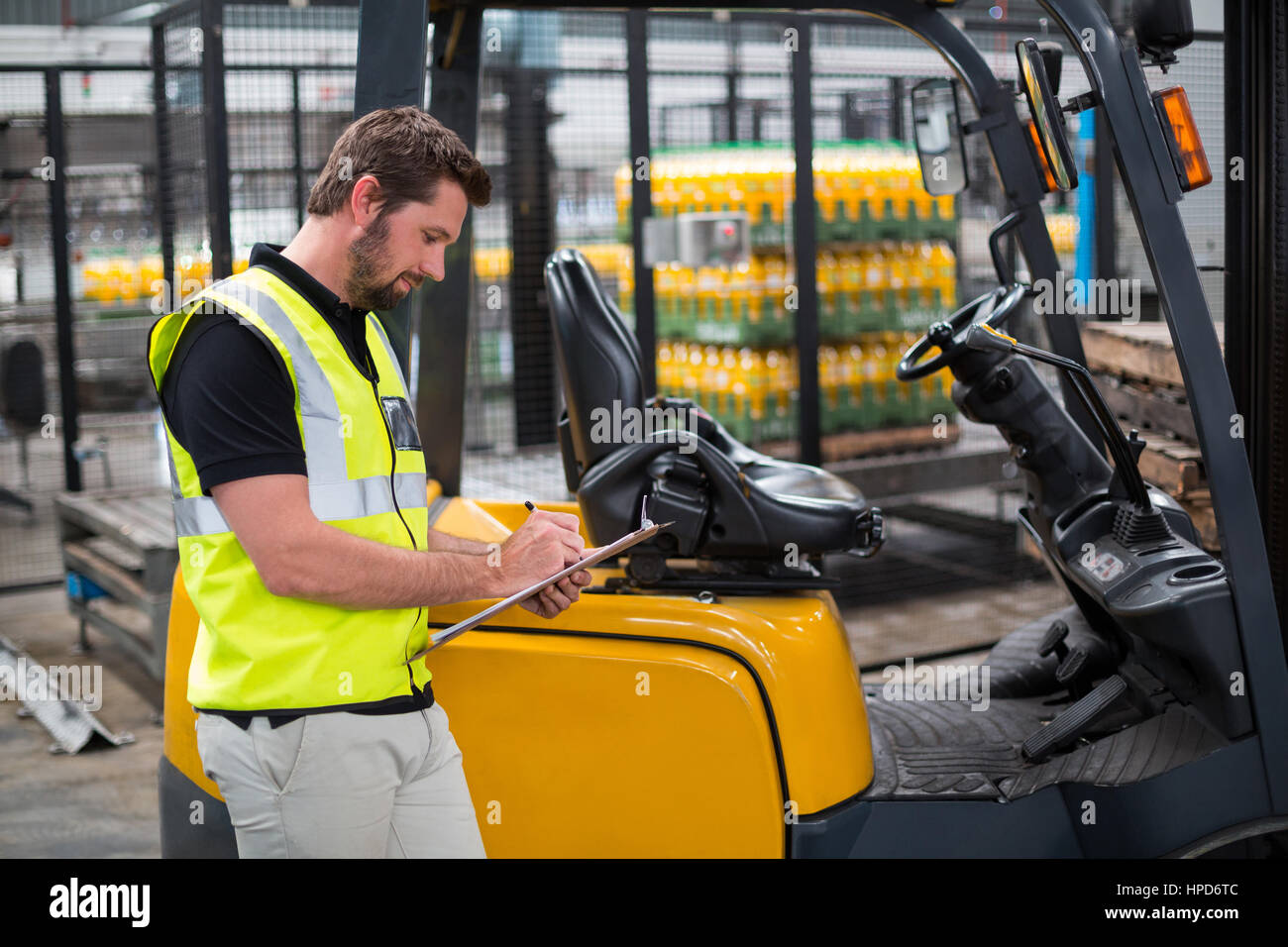 Attentive factory worker writing on clipboard in factory Stock Photo ...