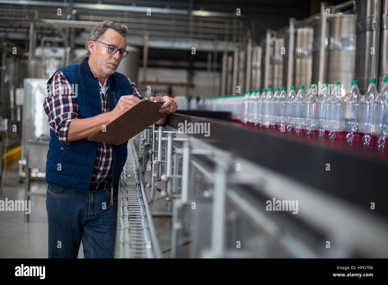 Male factory worker maintaining record on clipboard in drinks ...