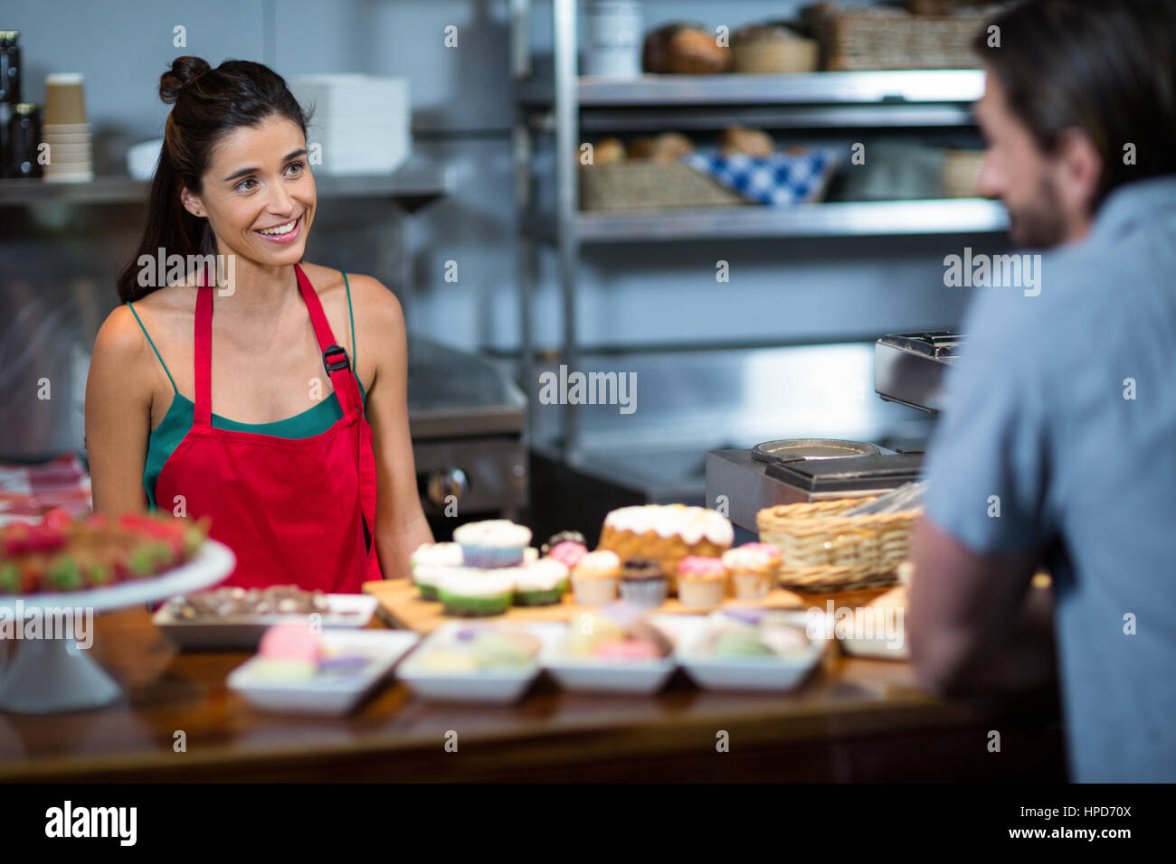 Smiling female staff interacting to customer at counter in bake shop ...