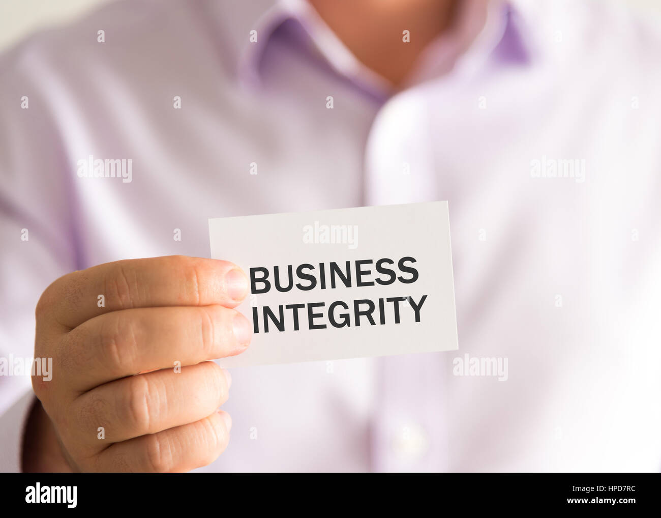 Closeup on businessman holding a card with text BUSINESS INTEGRITY ...
