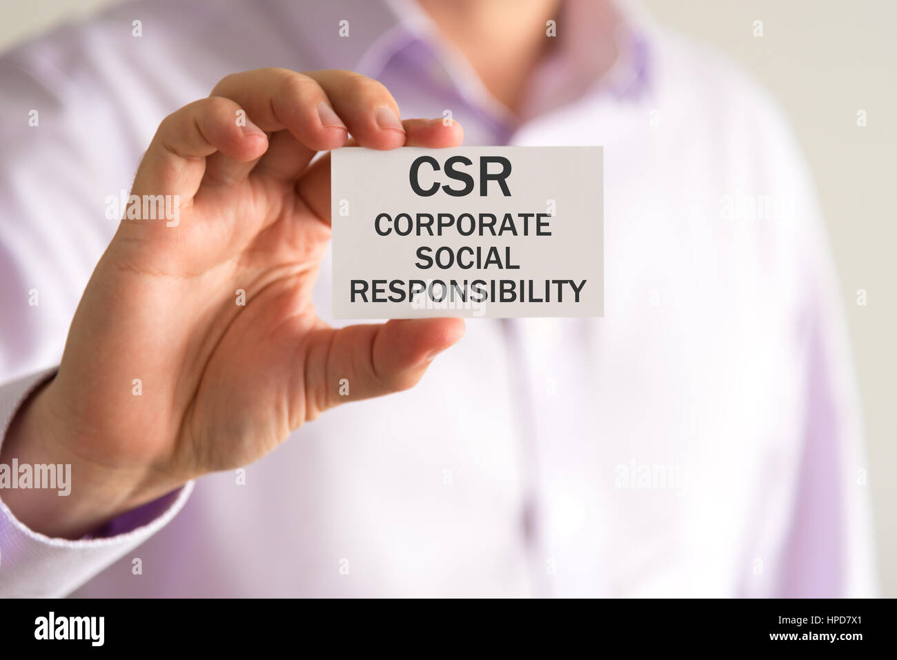 Closeup on businessman holding a card with text CSR Corporate Social ...