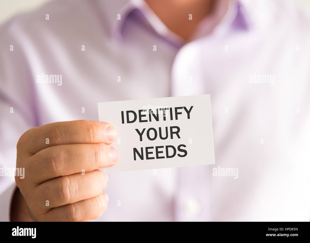 Closeup on businessman holding a card with text IDENTIFY YOUR NEEDS ...