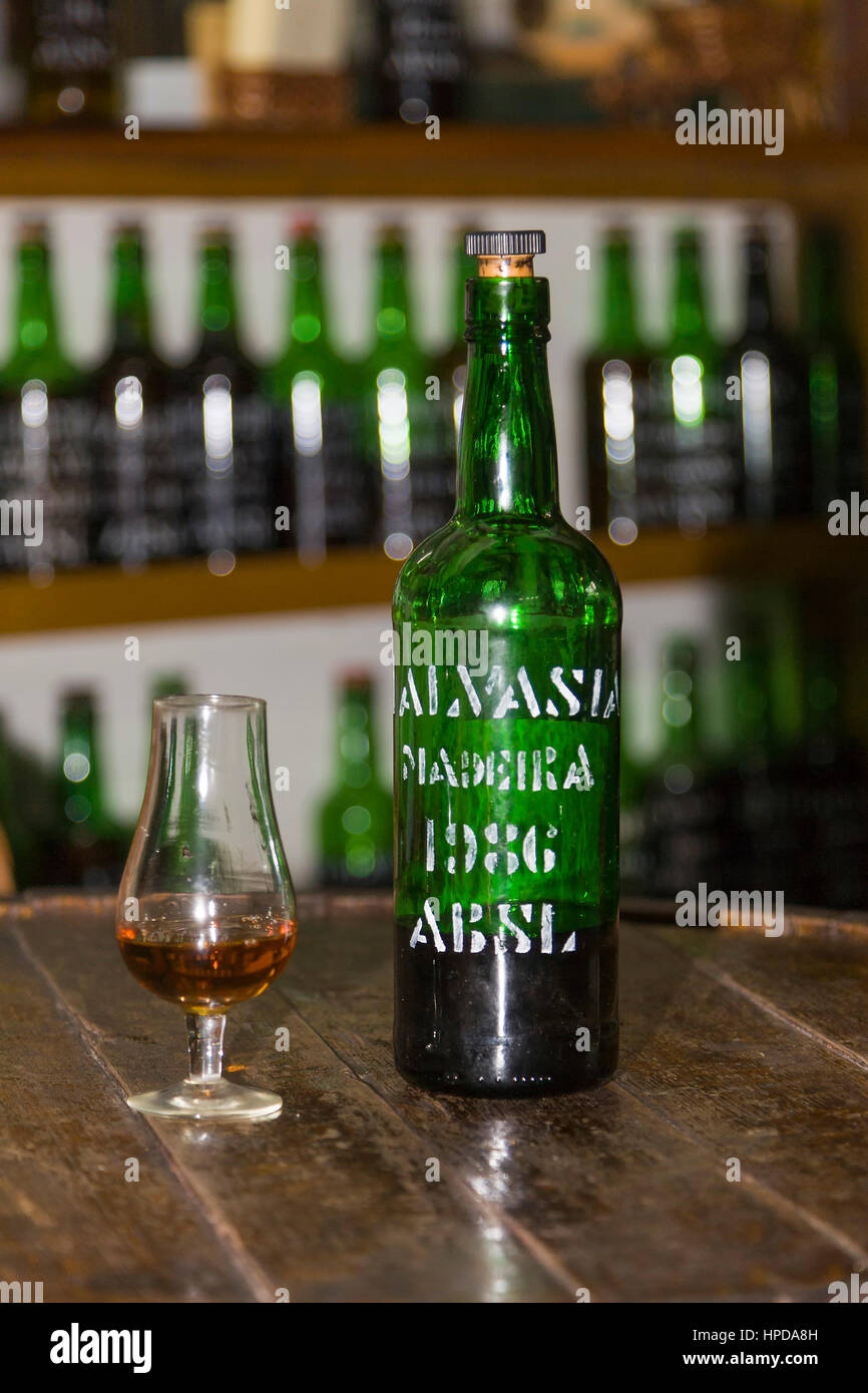 Bottle of madeira wine and wineglass on the winebarrel in Funchal ...