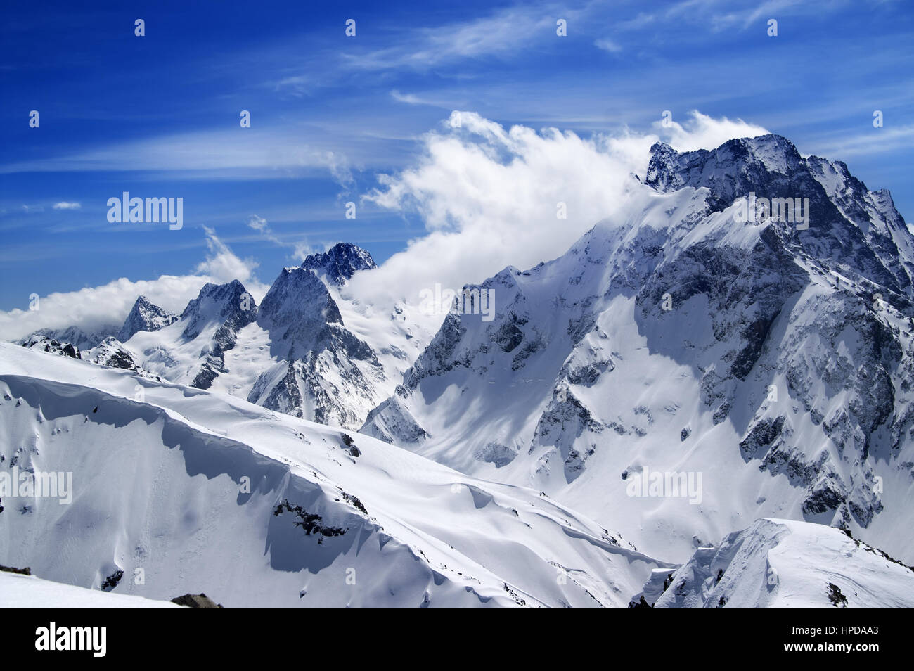 Winter mountains with snow cornice and blue sky with clouds in nice sun ...