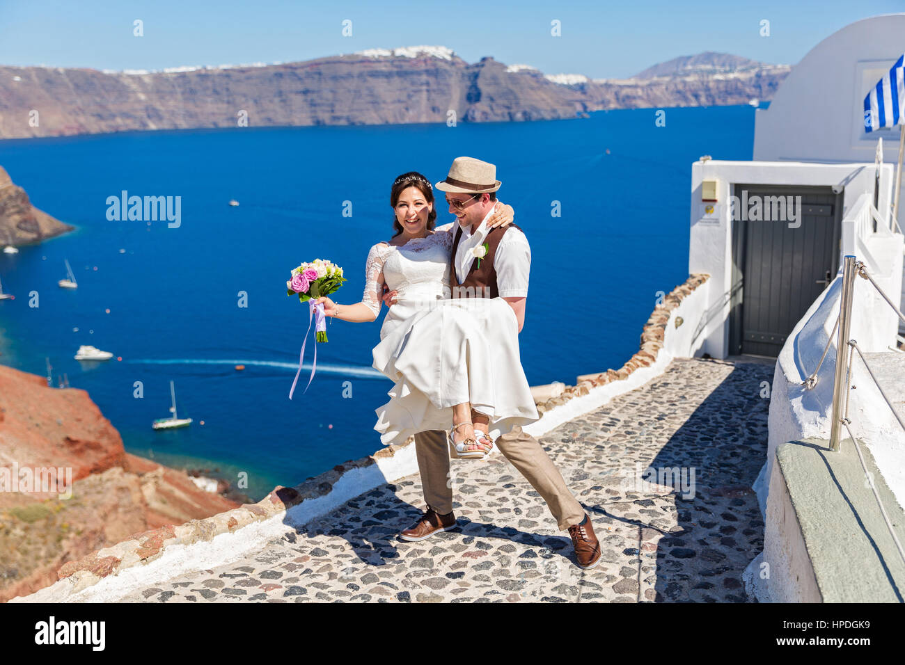 Cheerful wedding couple on Santorini island, Greece. Groom is holding ...