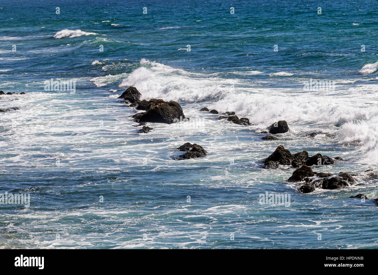 White waves and blue ocean washing over rocks at sea shore Stock Photo ...