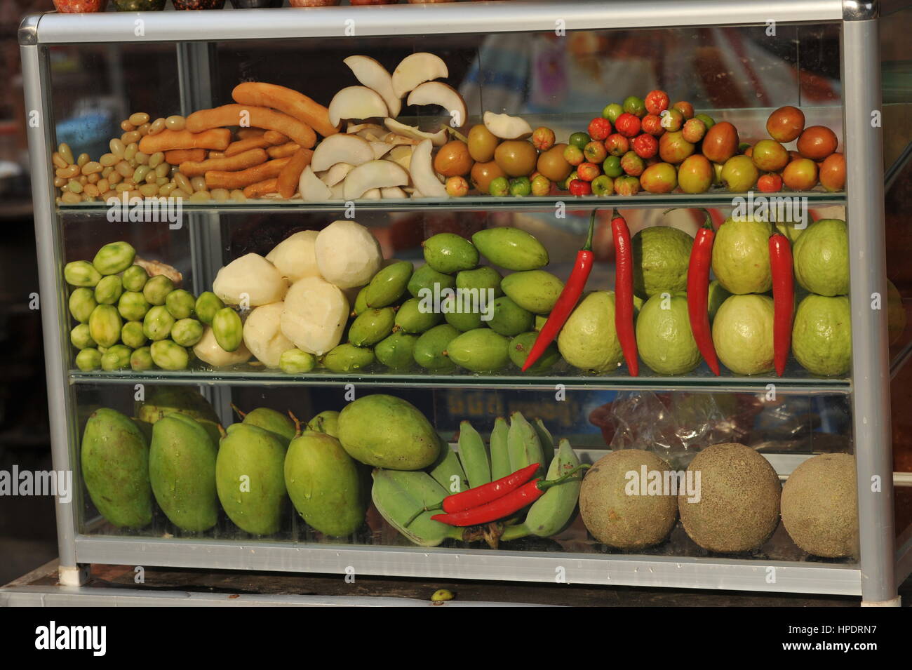 sunlit tropical fruit display at a street stall including mangoes ...