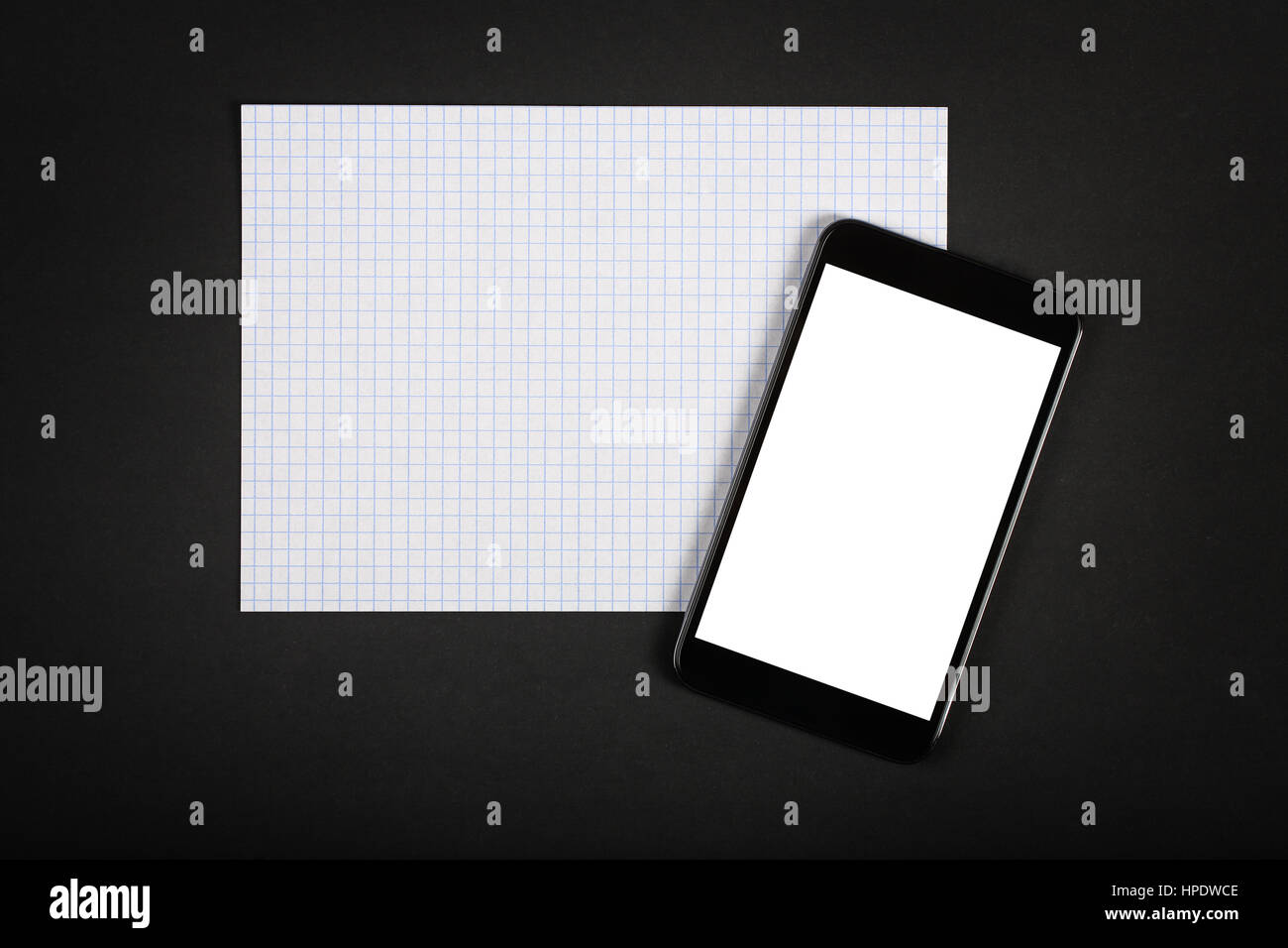 Generic smartphone with blank screen and sheet of paper on black desk ...