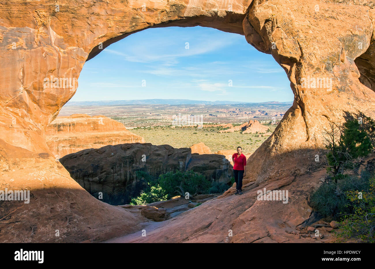 A young female hiker poses for scale at scenic Partition Arch in Arches ...