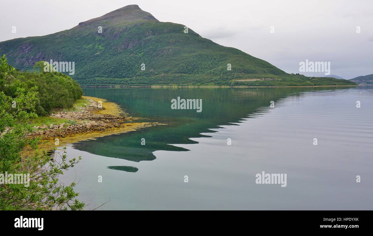 Mountains reflecting over clear turquoise water in the Lofoten Islands ...