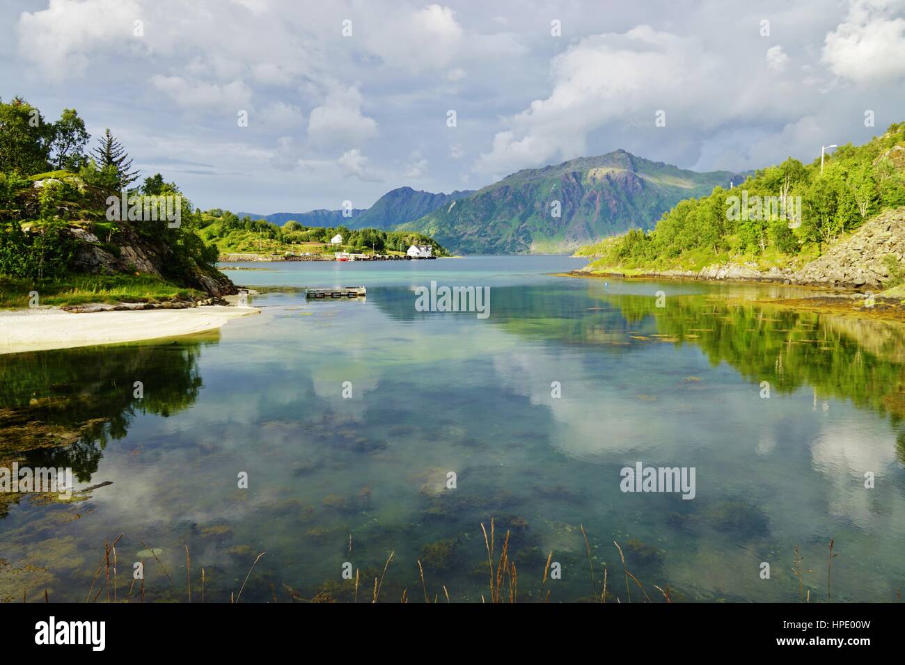 Mountains reflecting over clear turquoise water in the Lofoten Islands ...