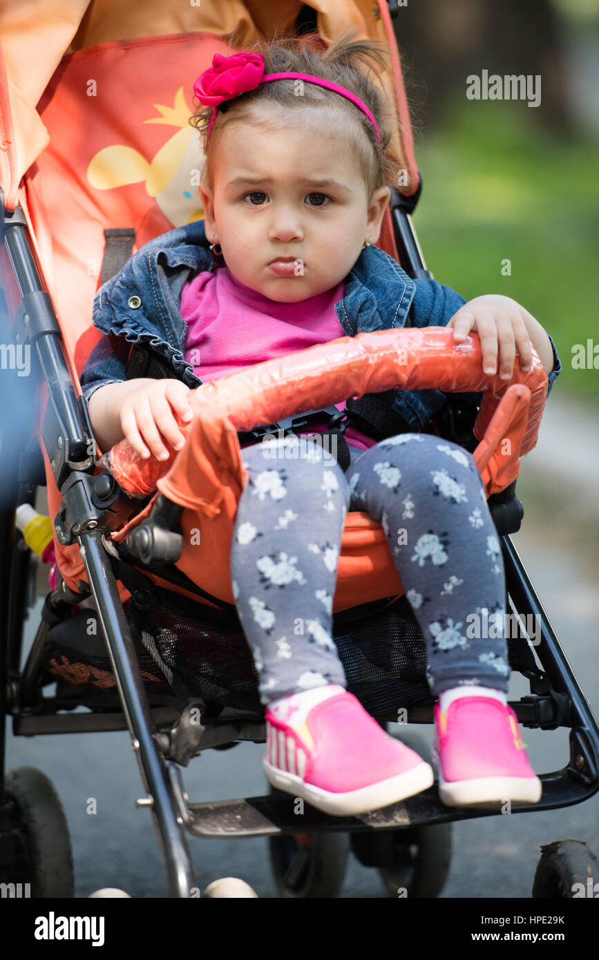 little and very beautiful baby girl sitting in the pram and waiting for ...