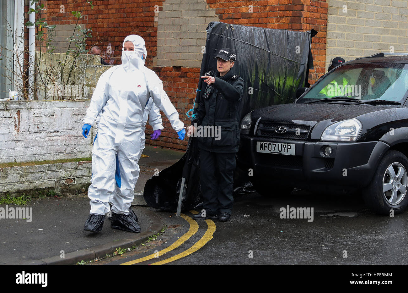 Forensic officers leave the scene through a fenced off alleyway on ...