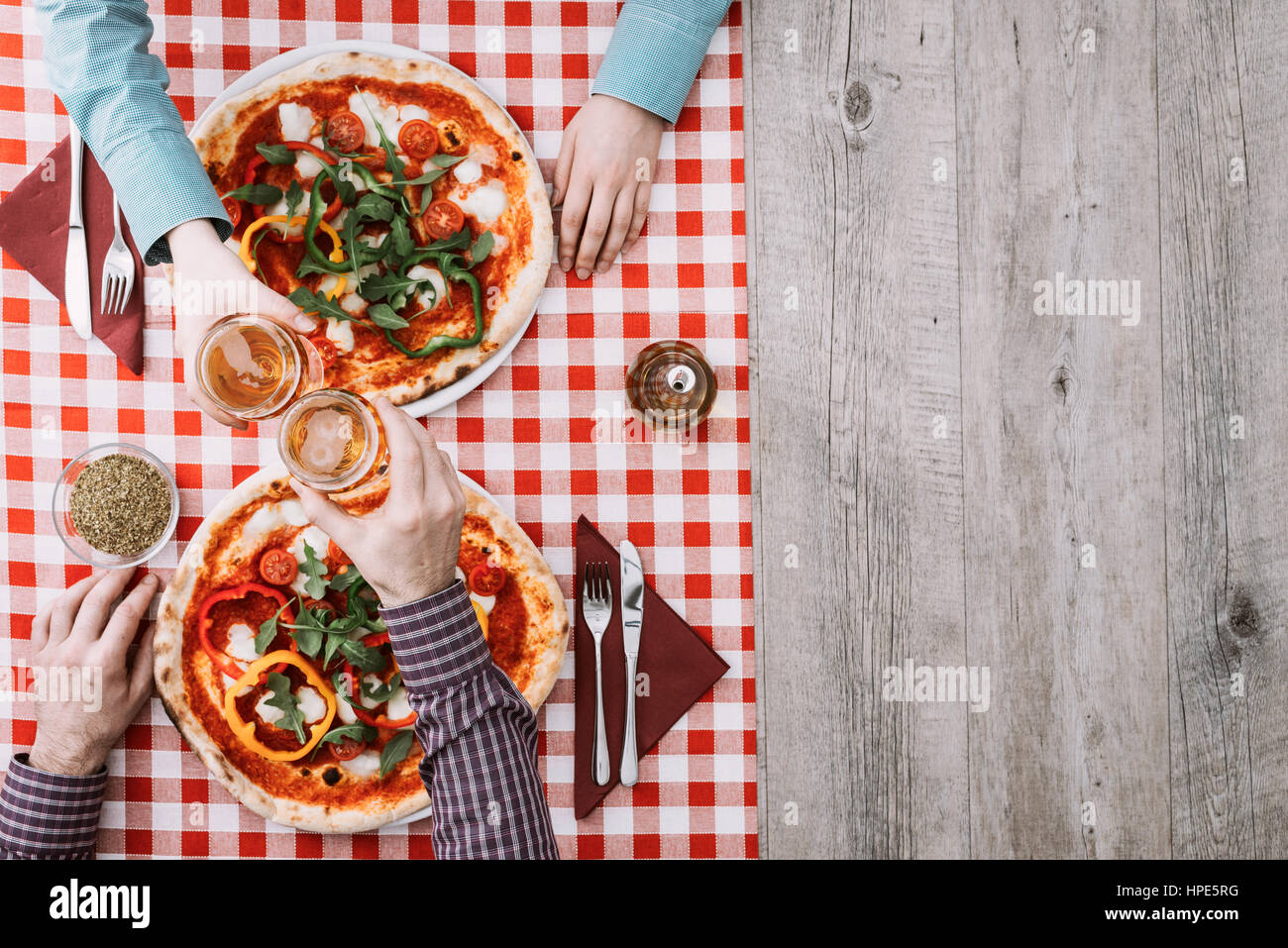 Two people eating a vegetable pizza at the restaurant, they are ...