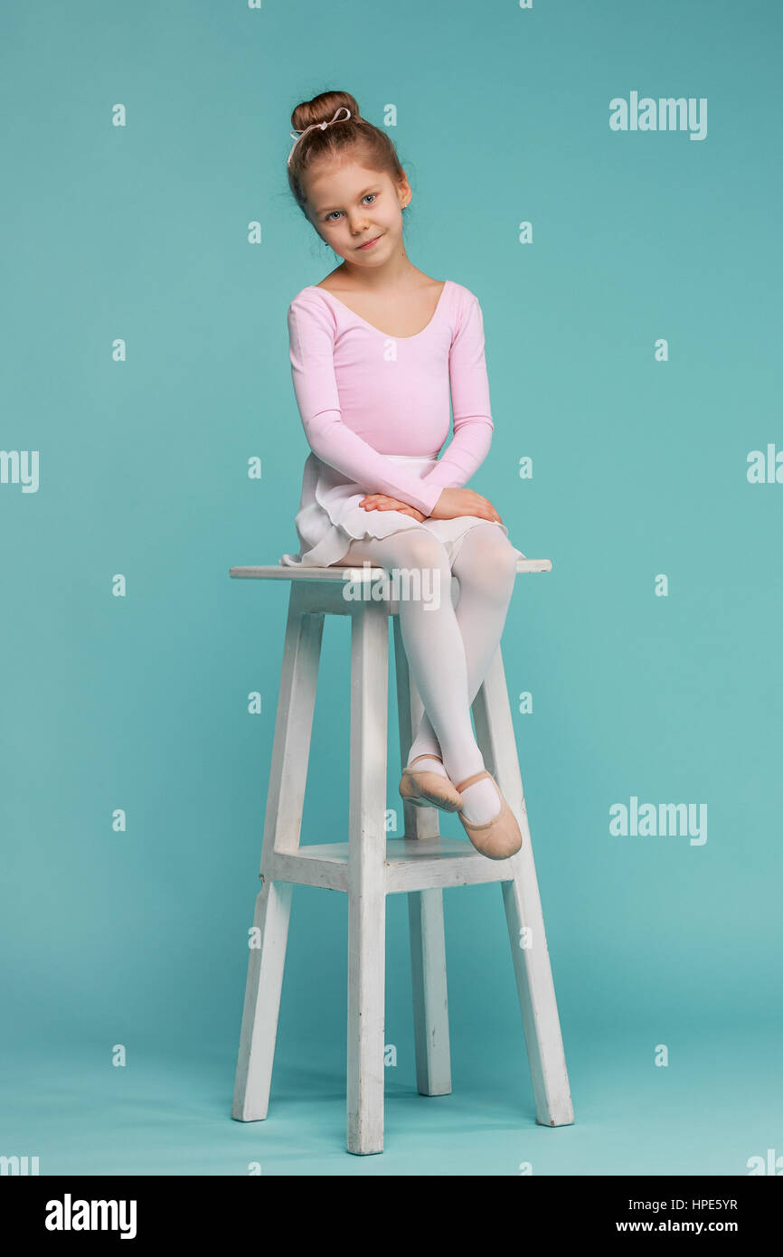 The little girl as balerina dancer sitting on white wooden chair at ...