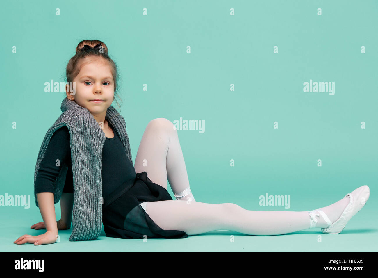 The little girl as balerina dancer sitting on white wooden chair at ...