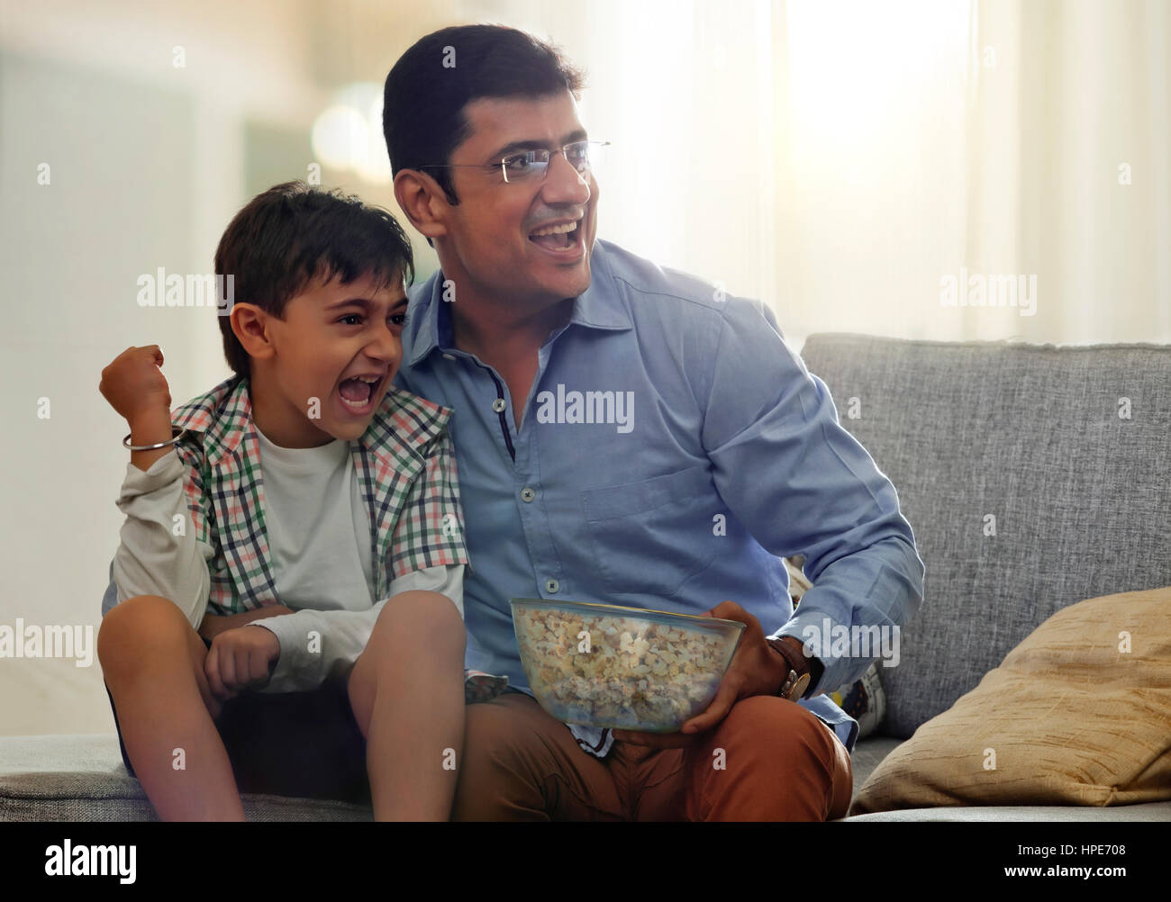 Father and son watching television and eating popcorn Stock Photo - Alamy