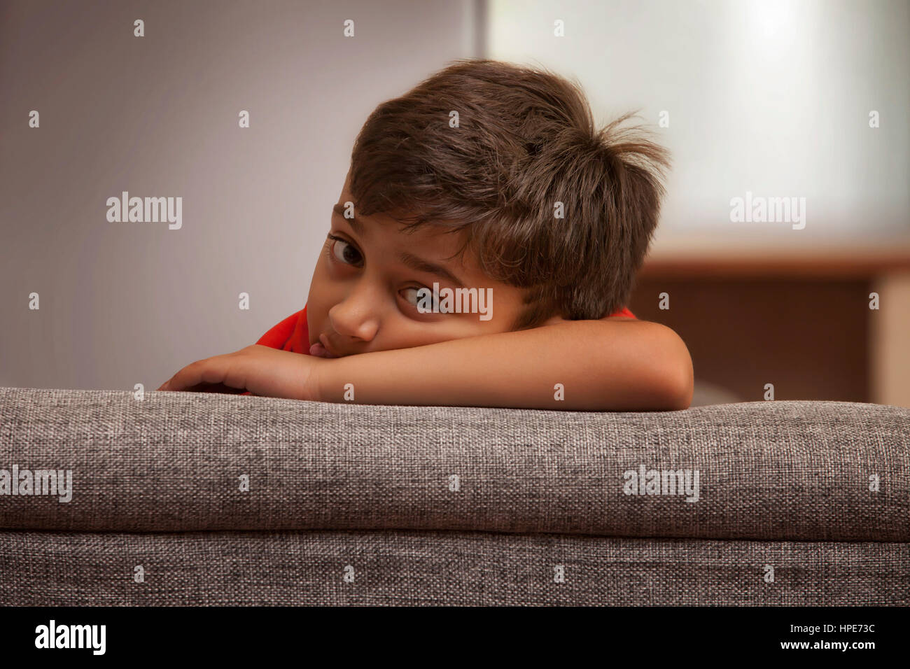 Portrait of boy leaning on sofa Stock Photo - Alamy
