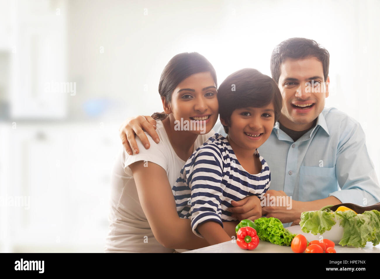 Portrait of smiling parents with their son sitting together at kitchen ...