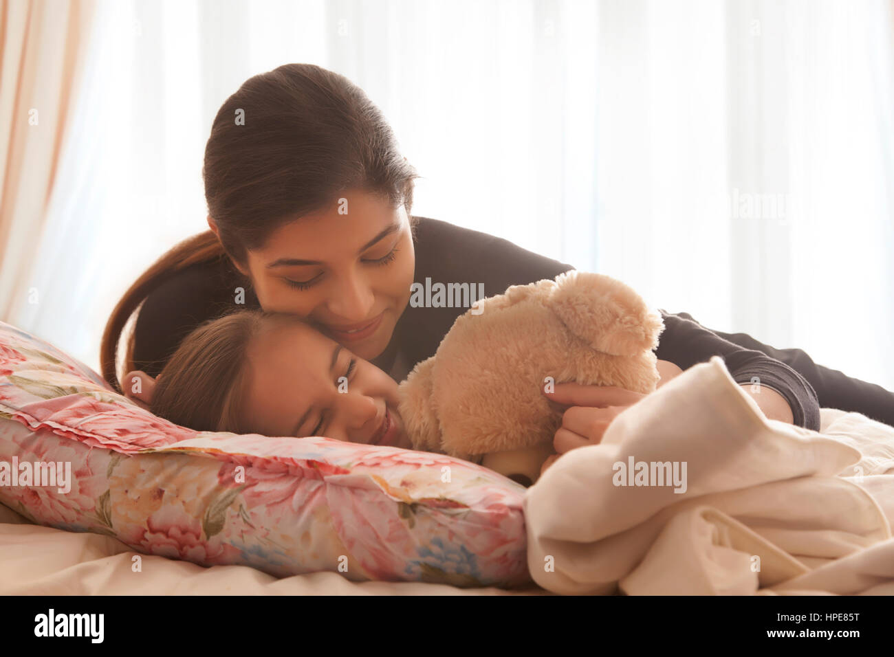 Mother kissing daughter in bed hi-res stock photography and images - Alamy