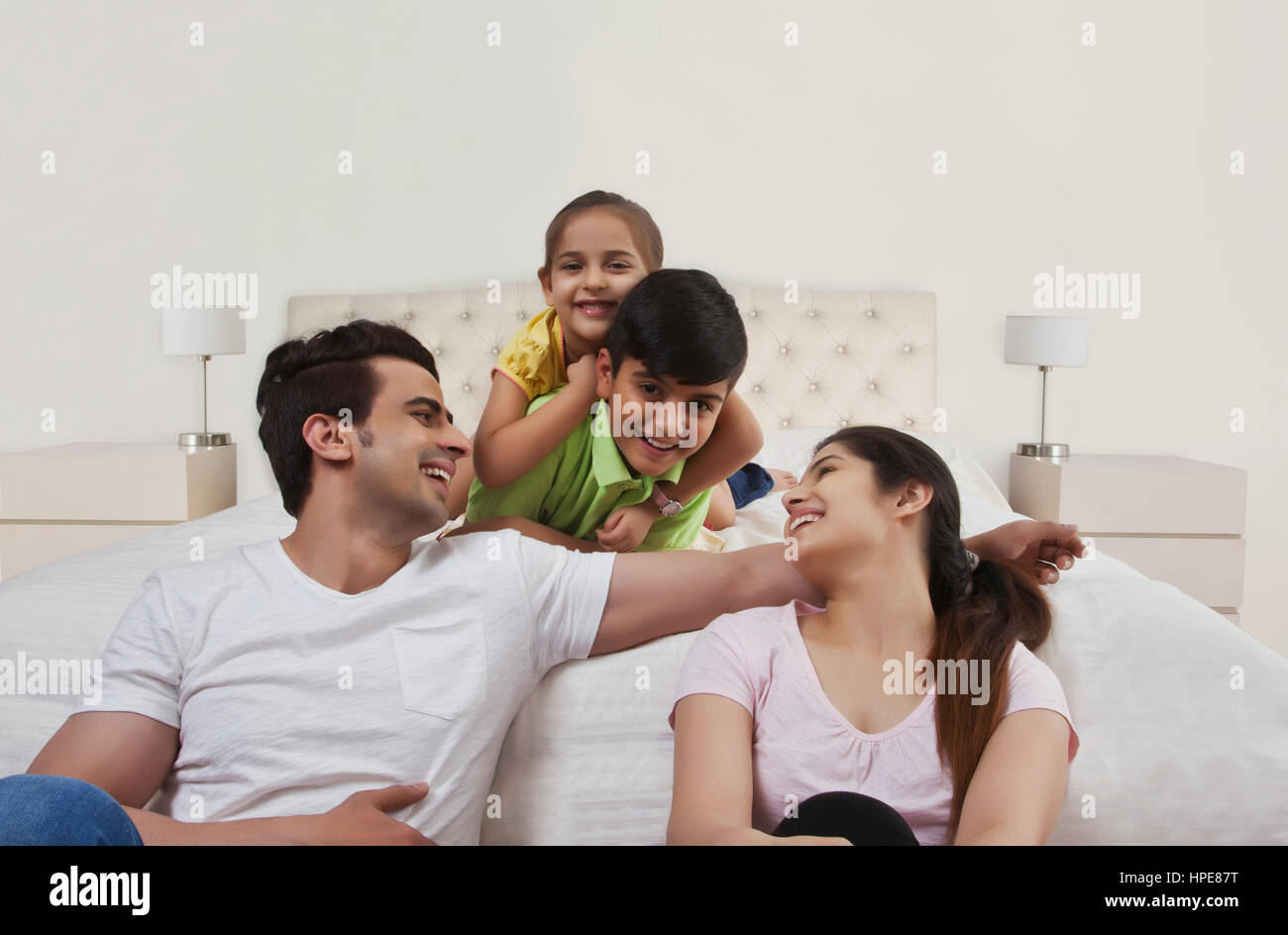 Smiling parents with their children relaxing in bedroom Stock Photo - Alamy