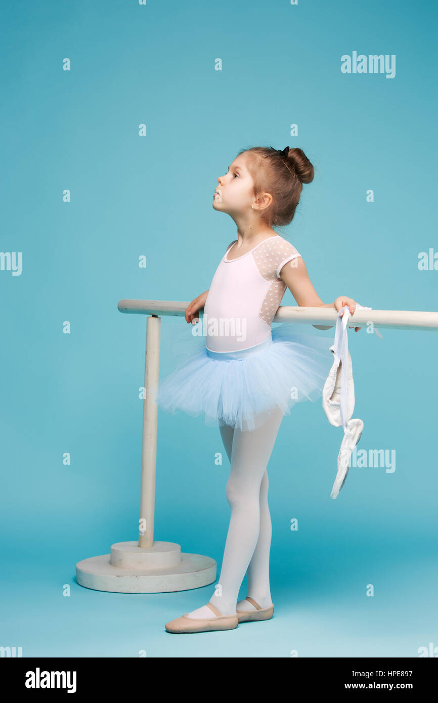 The little girl as balerina dancer posing near ballet rack on blue ...