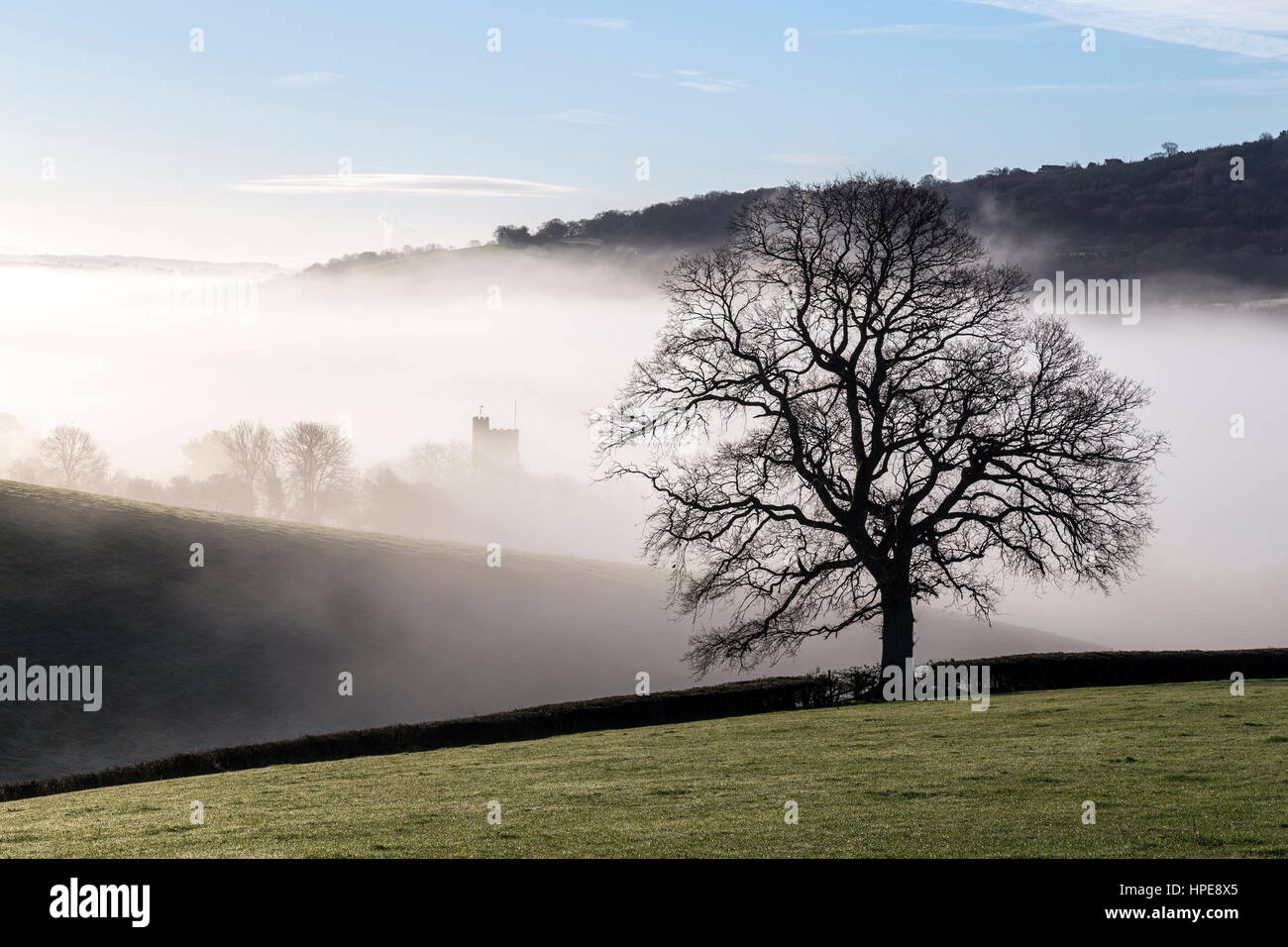 Mist rolls over a combe or coombe a valley containing the village of ...
