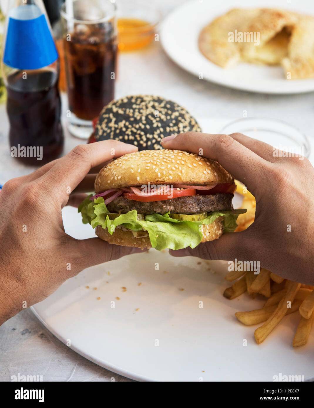 Man eating burgers at table, pov view Stock Photo - Alamy