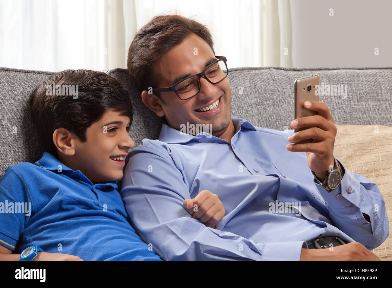 Father and son looking at mobile phone Stock Photo - Alamy