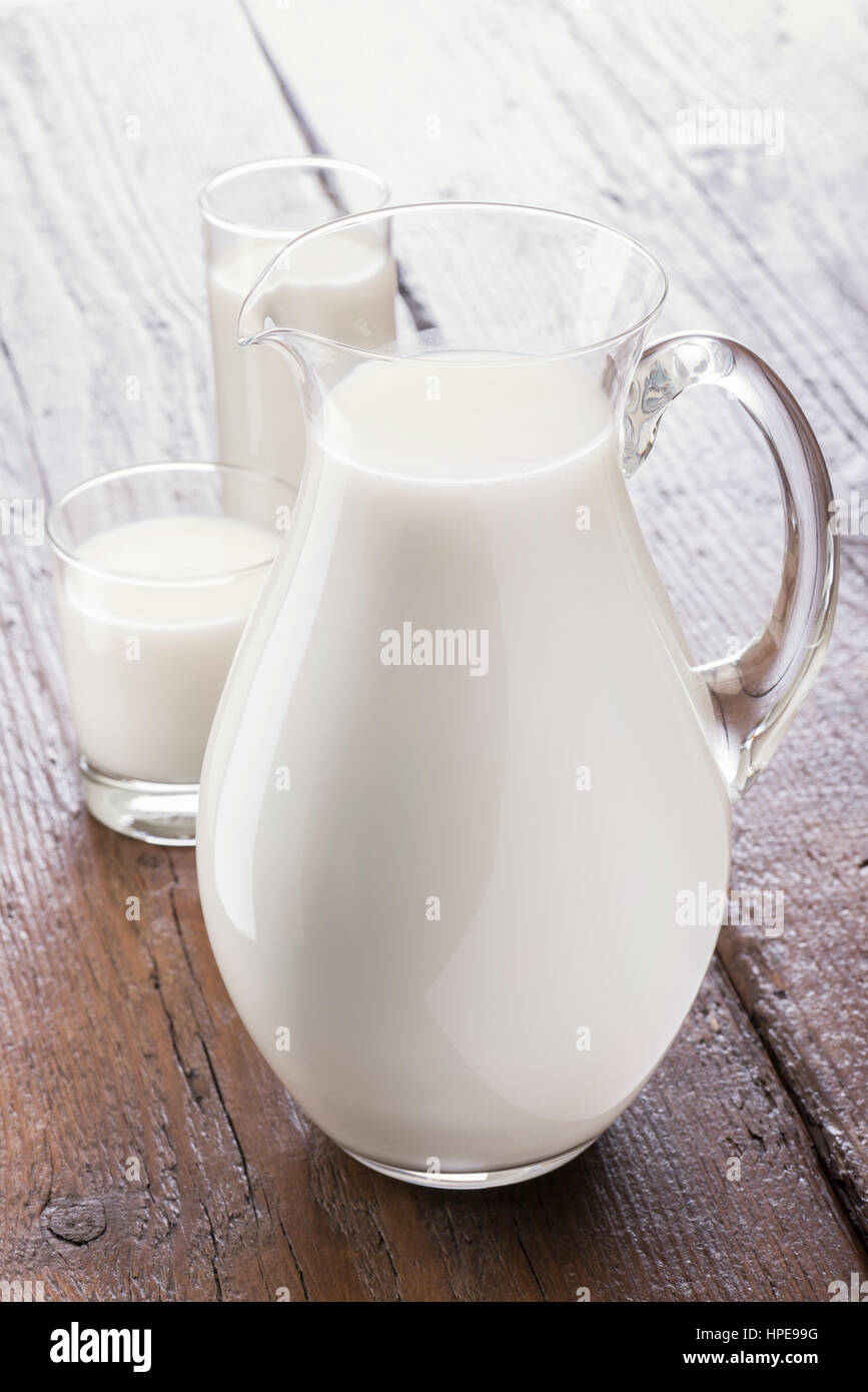 glass jug full of milk, on wooden table Stock Photo - Alamy