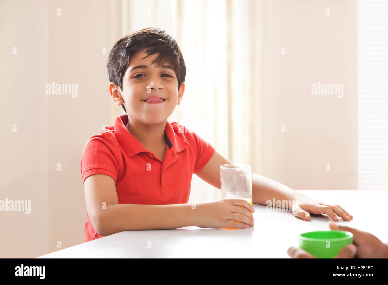 Boy enjoying juice sitting at dining table Stock Photo - Alamy