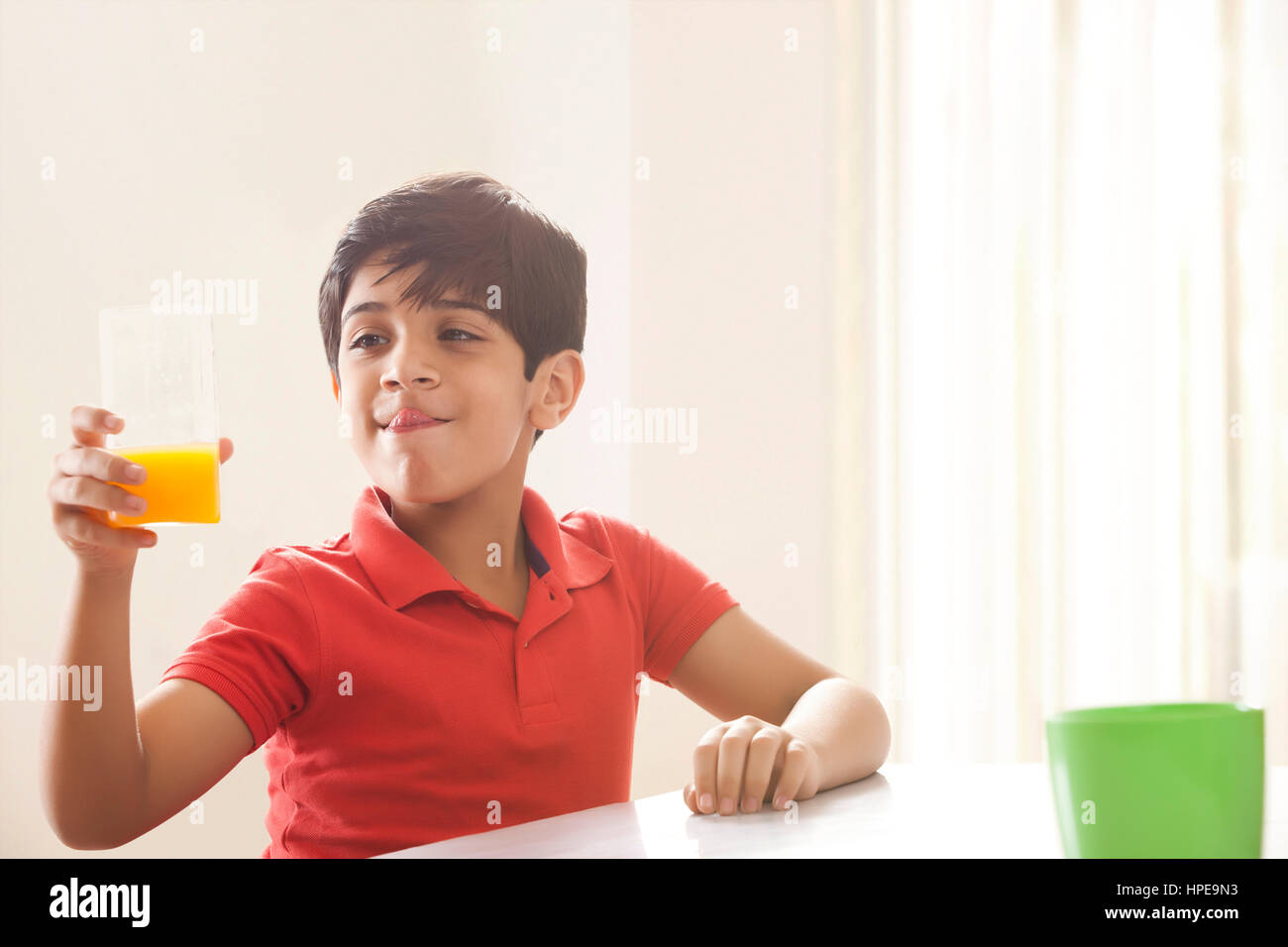 Boy enjoying juice sitting at dining table Stock Photo - Alamy