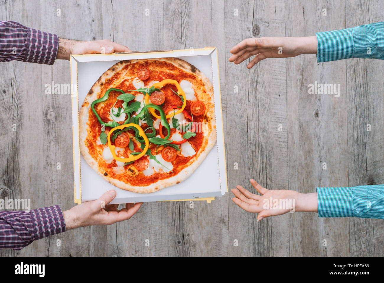 Pizza delivery at home: a man is handing a pizza in a box to a woman ...