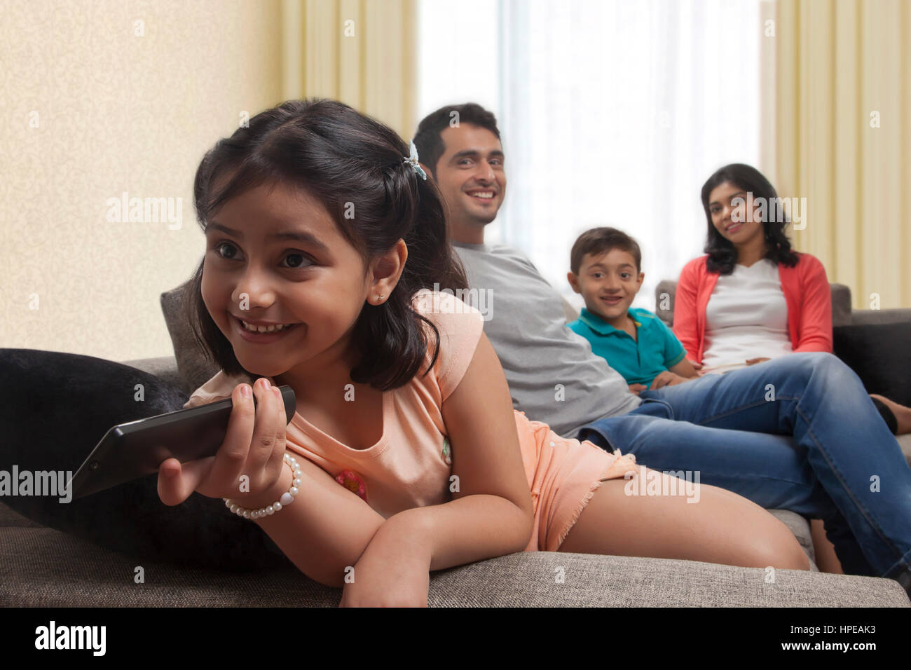 Smiling girl watching TV with family Stock Photo - Alamy