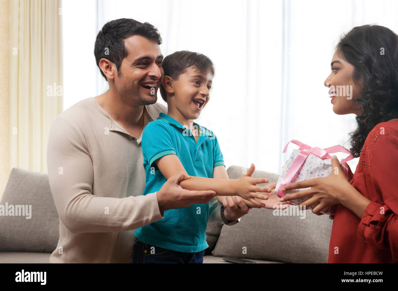 Father holding son while mother snatching gift Stock Photo - Alamy